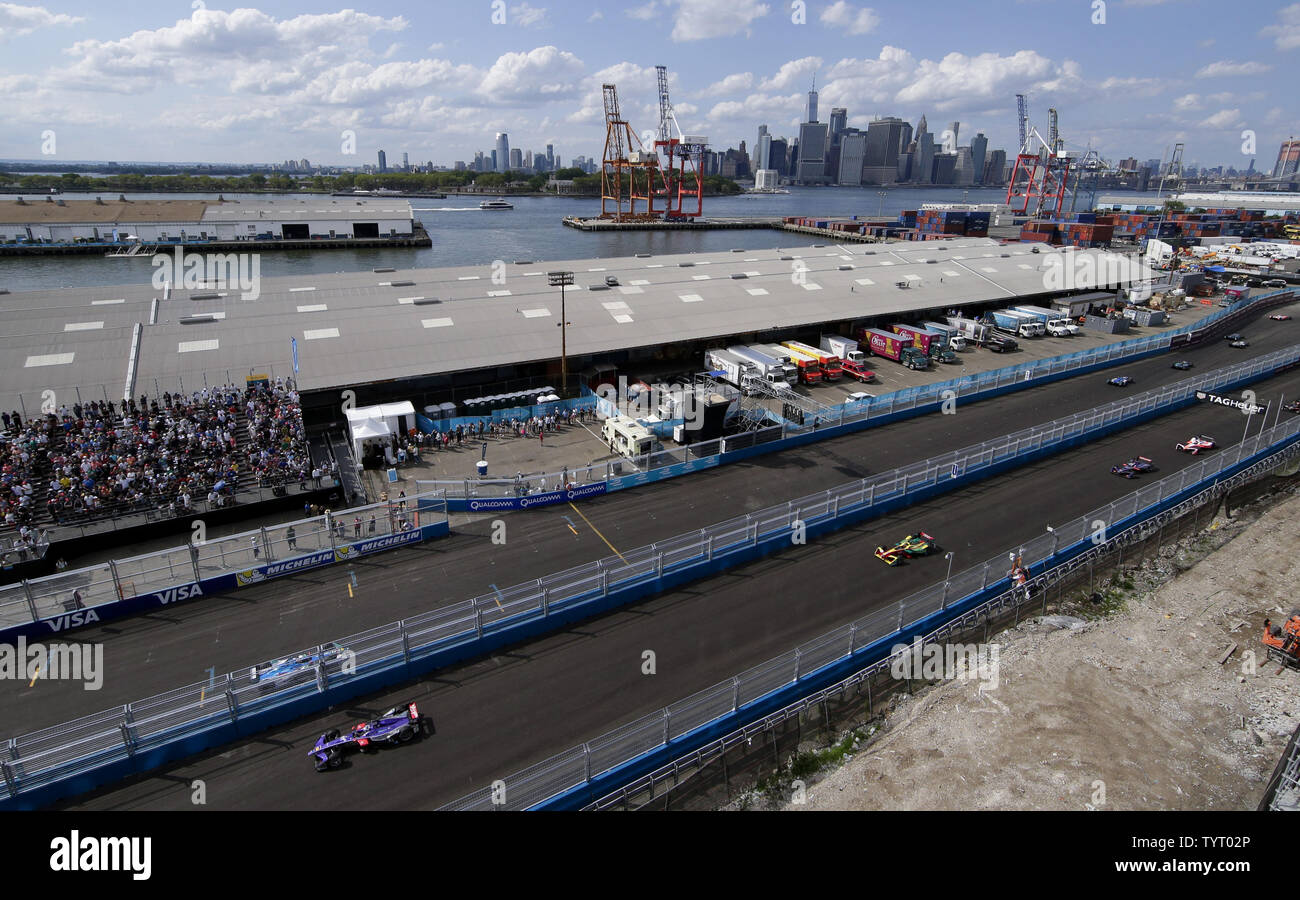 Competing cars race around the track with the Manhattan skyline and One ...