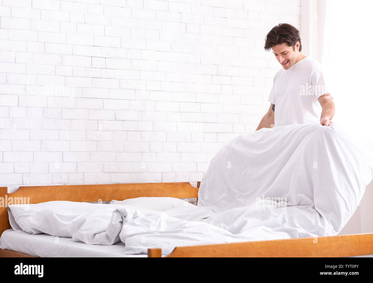 Millennial guy making bed in morning, domestic chores concept Stock ...