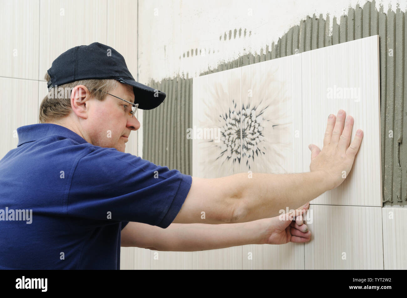 Tiler is installing a ceramic tile on a wall in a bathroom Stock Photo ...