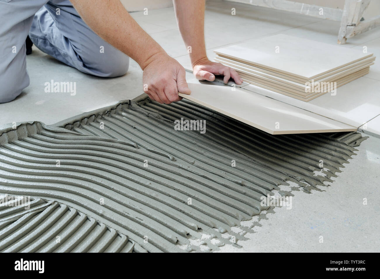 The hands of the tiler are laying the ceramic tile on the floor Stock ...
