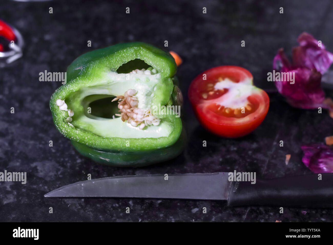 cut capsicum and tomato and knife on granite background Stock Photo - Alamy