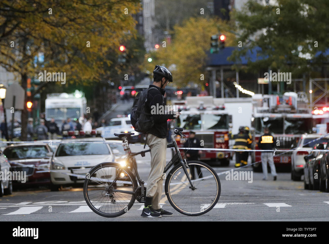 A man on a bicycle stops at a Police line that blocks off the area ...