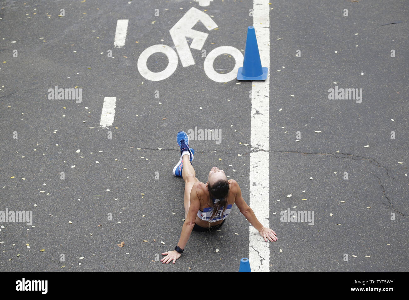 A runner falls to the ground after crossing the finish line at the NYRR ...