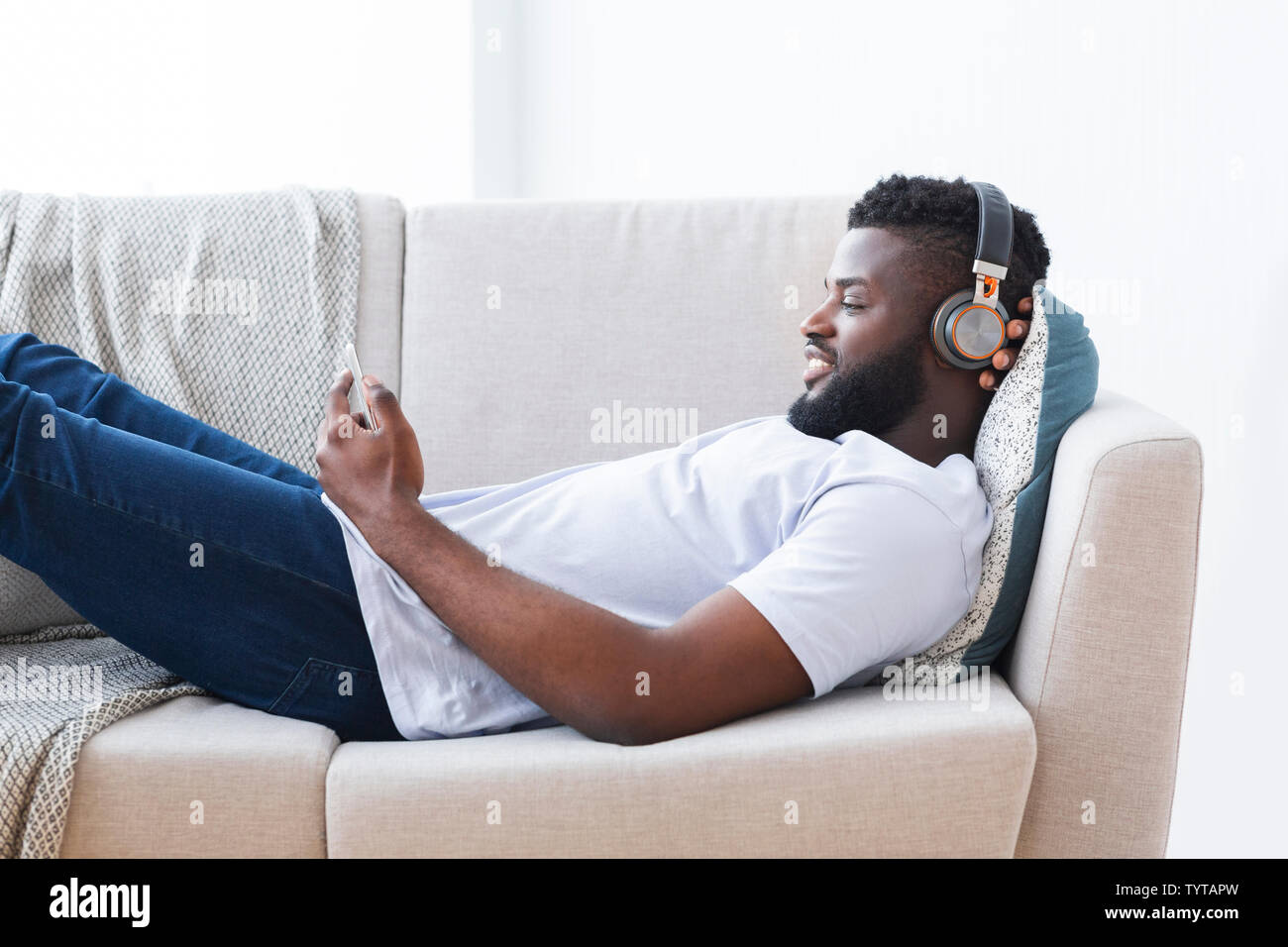 African guy watching videos on smartphone, using mobile application ...