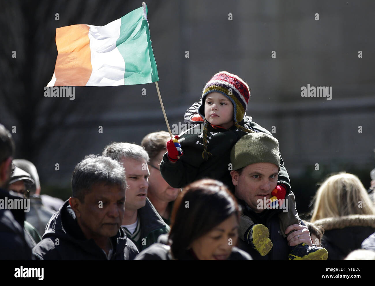 A child holds the flag of Ireland while watching the parade move up ...
