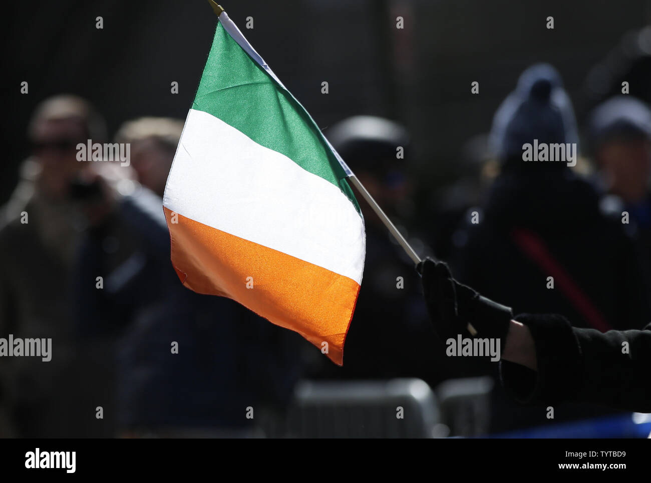 A woman holds the flag of Ireland while watching the parade move up ...