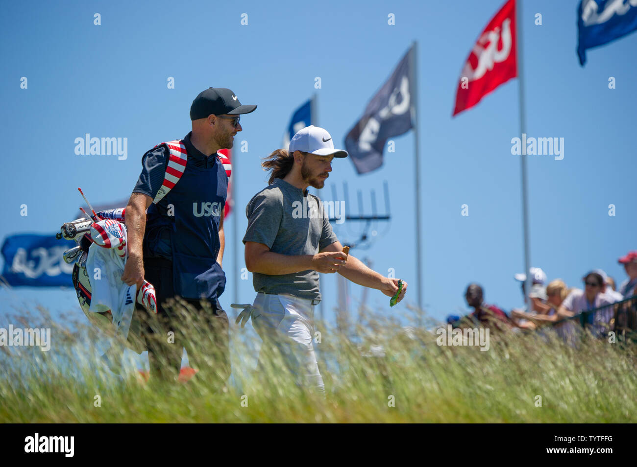 Tommy Fleetwood from England and caddy Ian Finnis walk on the first ...