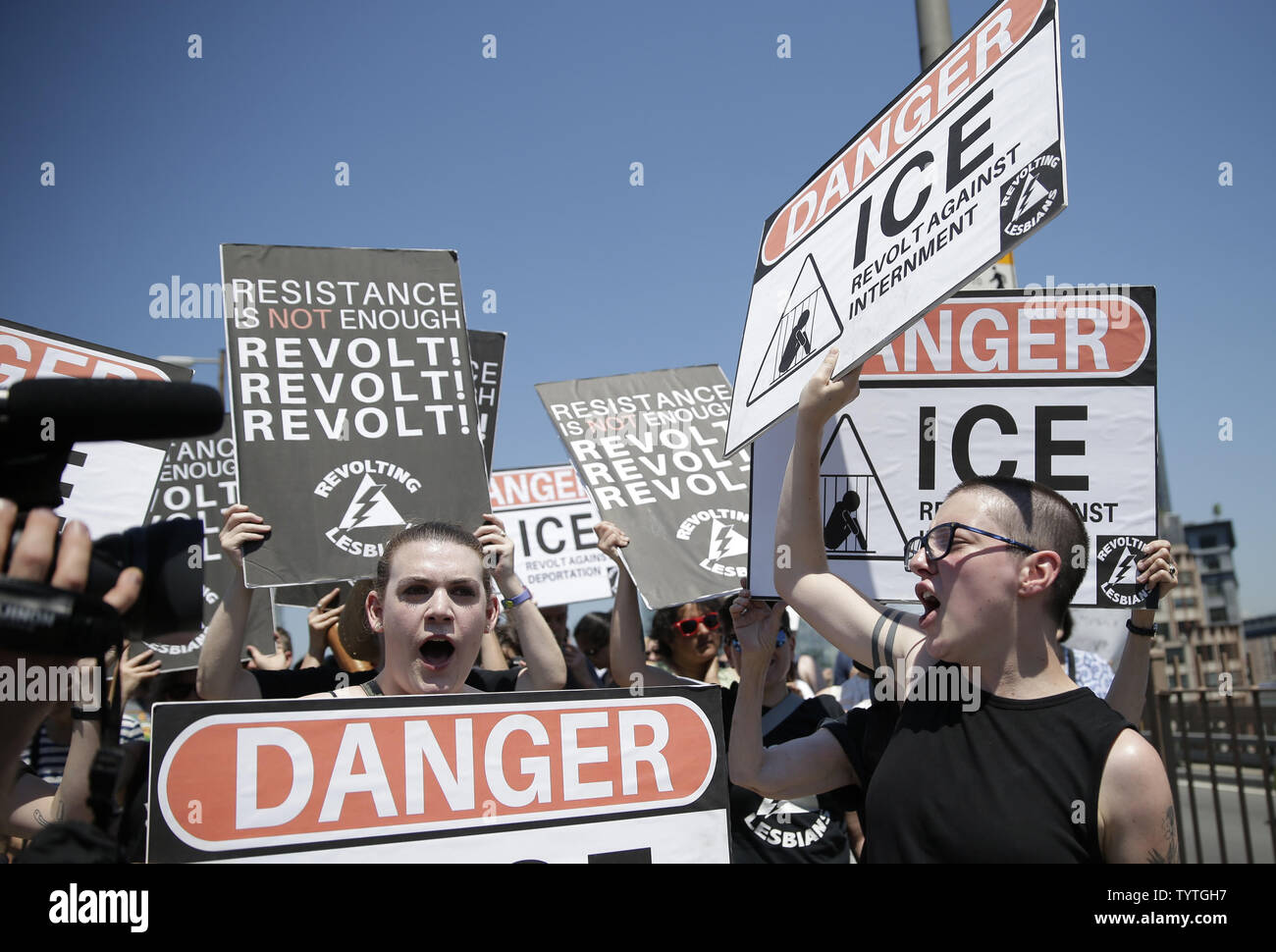 Protesters hold up signs as they walk across the Brooklyn Bridge at the ...