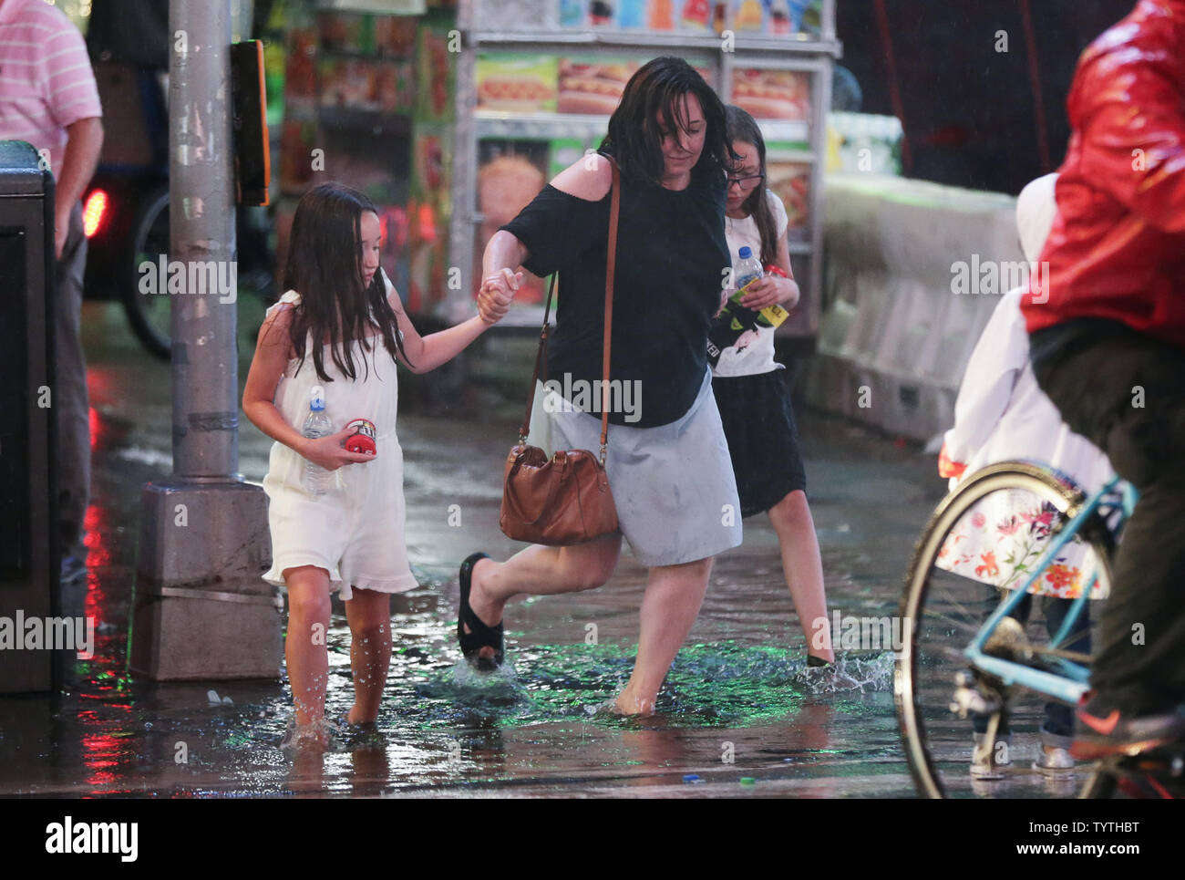 A woman and two children walk through a puddle as rain falls in Times ...