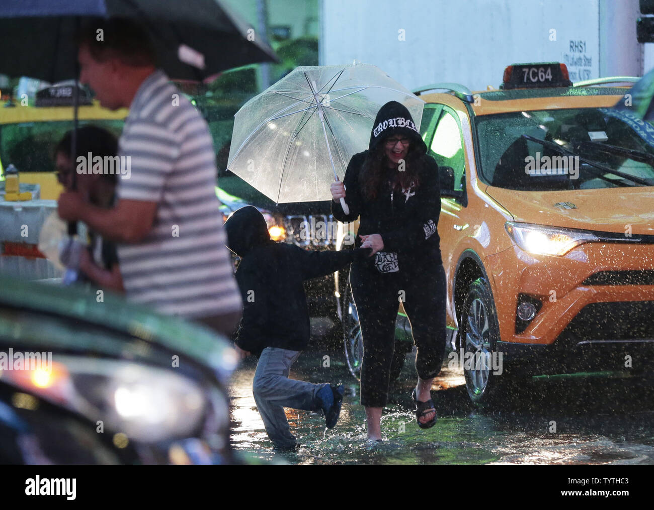 A woman and child walk through a puddle as rain falls in Times Square ...