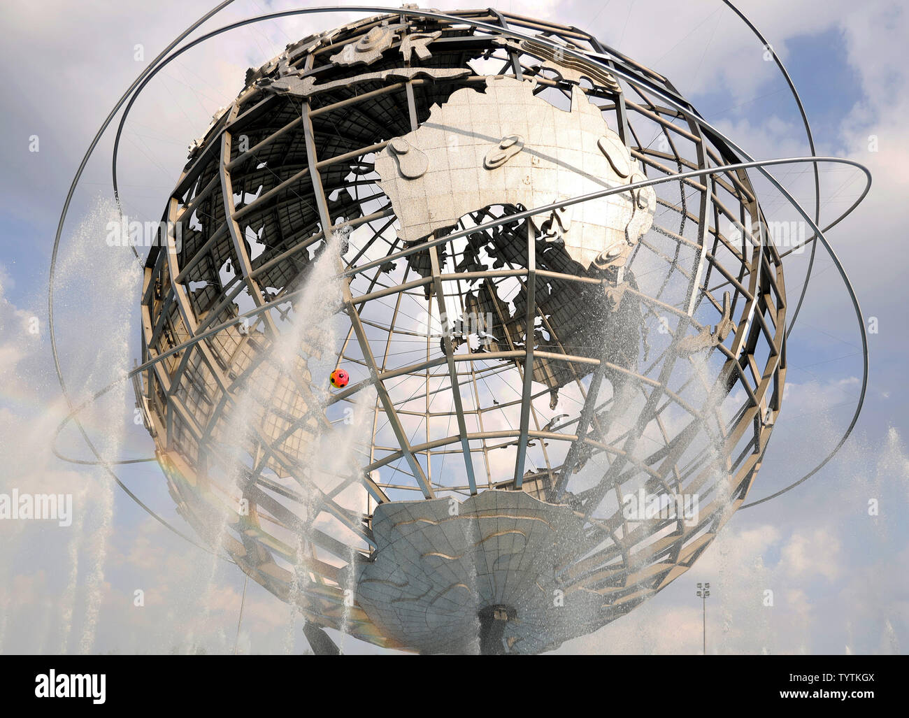 A boy tosses a ball in the air while playing in the fountain below the ...