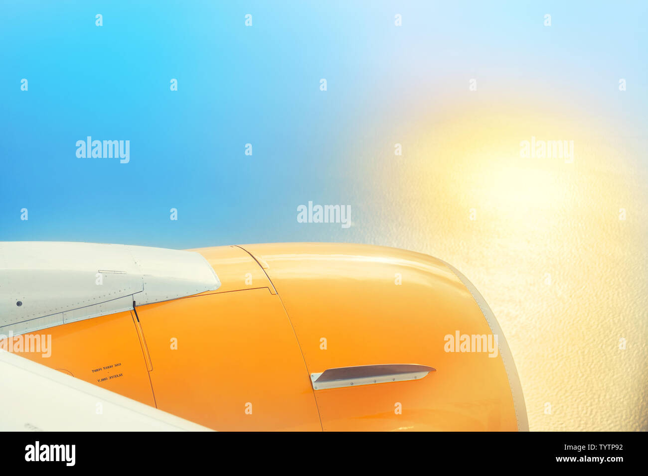 Close-up engine of plane flying over sea or ocean with sun reflection ...