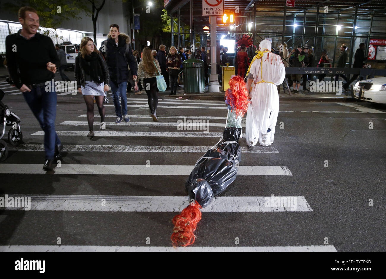 A girl drags a corpse behind her in costume as she crosses the street ...