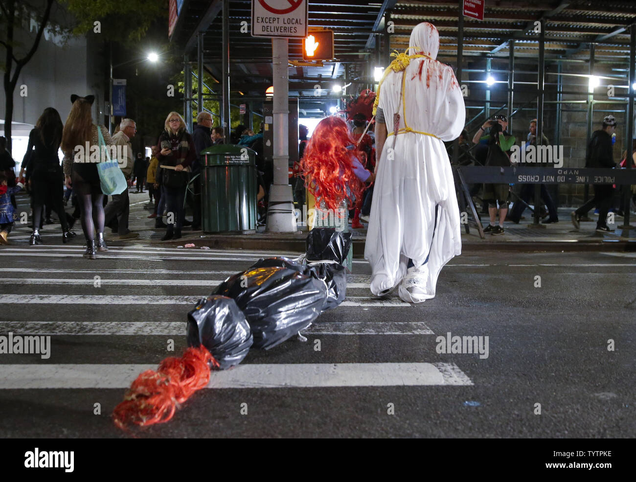 A girl drags a corpse behind her in costume as she crosses the street ...