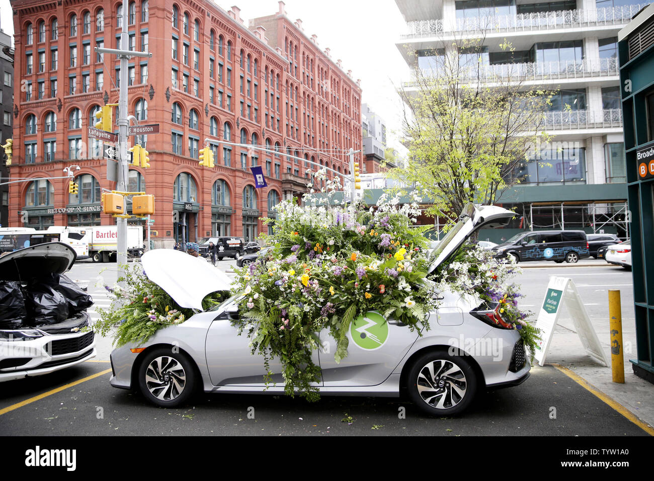 A car filled with flowers is parked opposite a car filled with trash ...