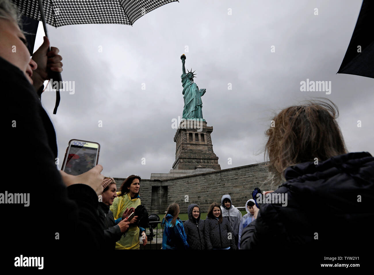 Tourists brave the wind and rain to visit the Statue of Liberty, on ...