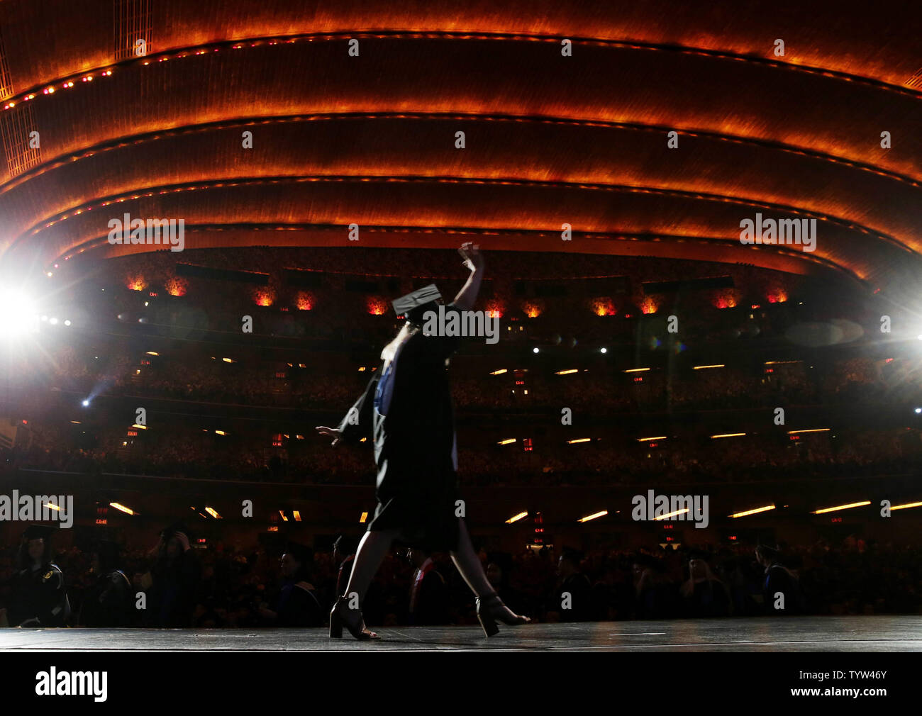 Graduates walk on stage to receive their degrees at the commencement ...