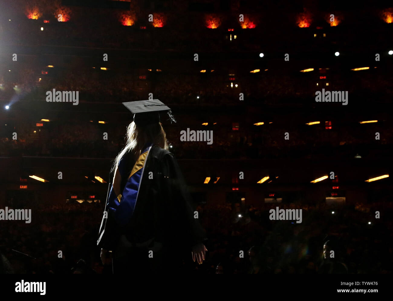 Graduates walk on stage to receive their degrees at the commencement ...