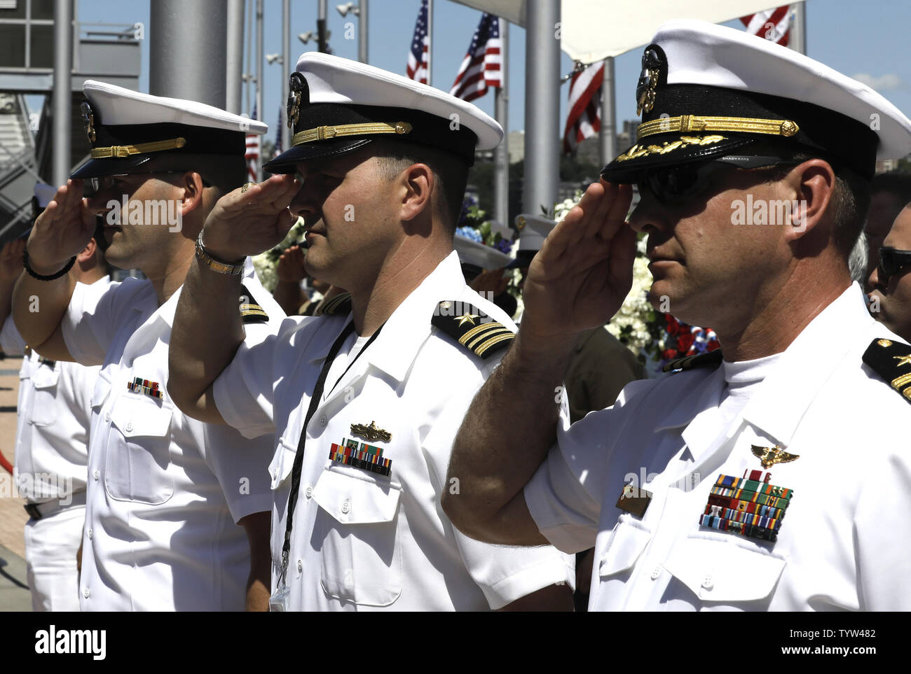 US Naval Officers salute and stand at attention during the playing of ...