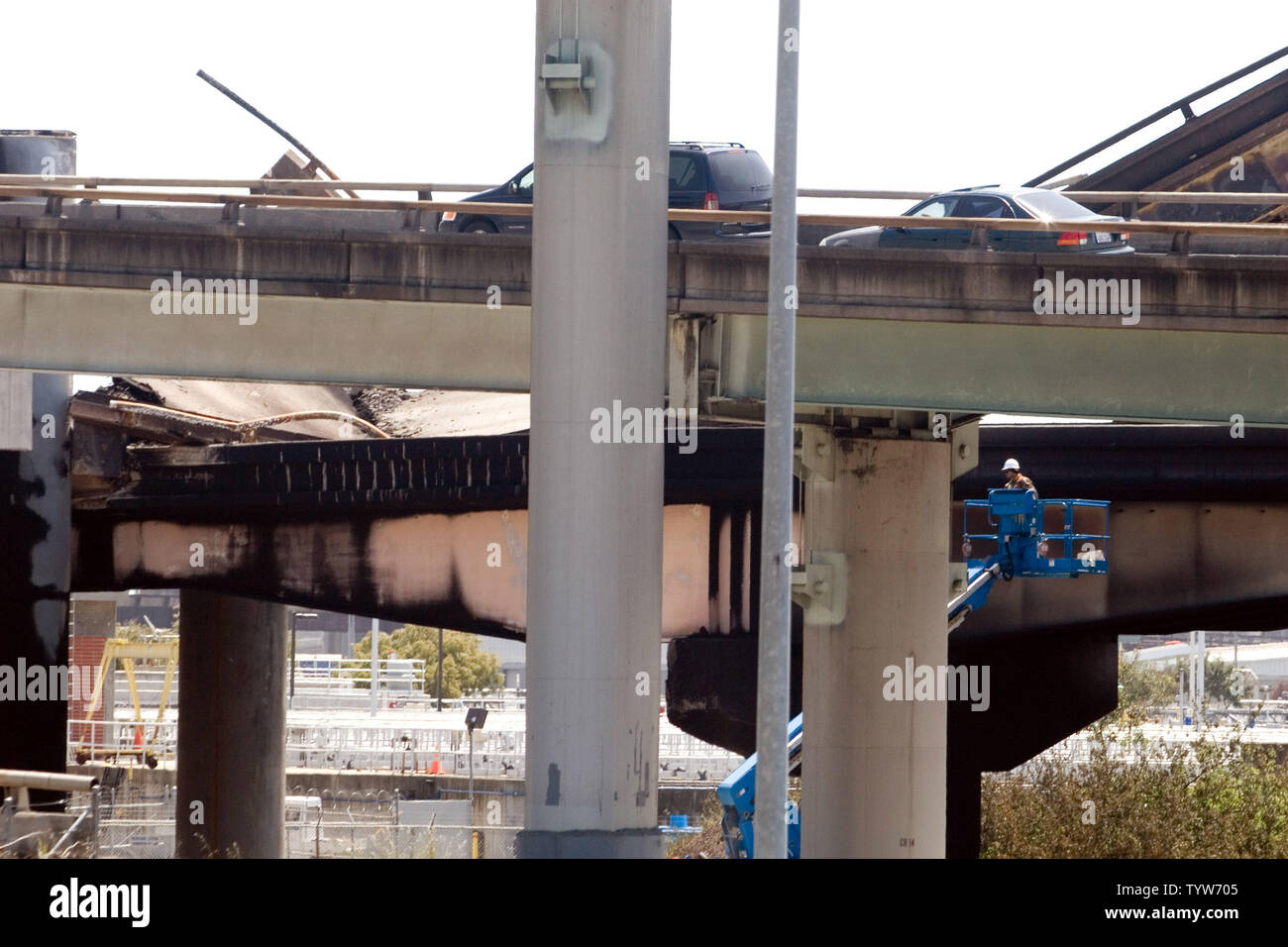 A worker in a crane inspects the damage to a collapsed section of ...