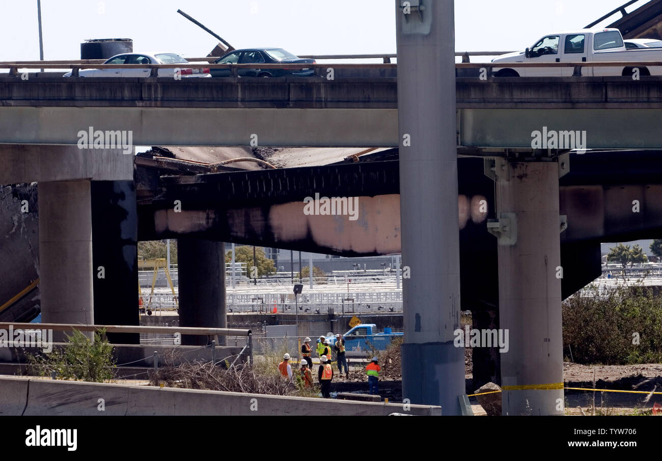Transportation department workers inspect a collapsed section of ...