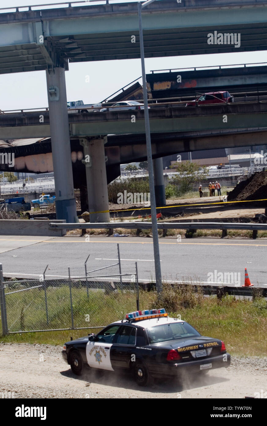 A Highway Patrol vehicle drives by a section of collapsed highway near ...