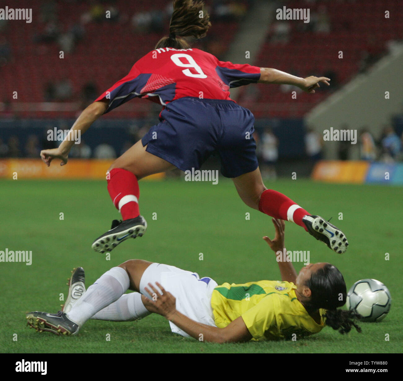 USA's Mia Hamm (#9) hops over Brazil's Daniela (on ground) to avoid a ...