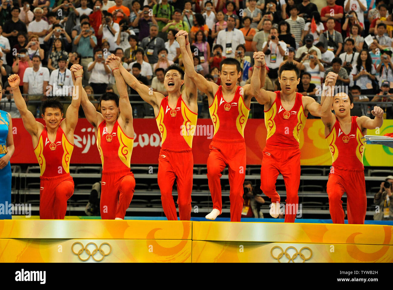 The Chinese men's gymnastics team join hands and run to the stage to ...