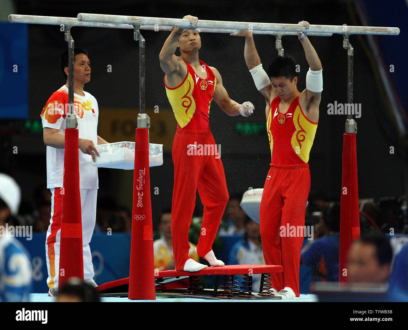China's Yang Wei (C) and Li Xiaopeng (R) rub chalk on the parallel bars ...