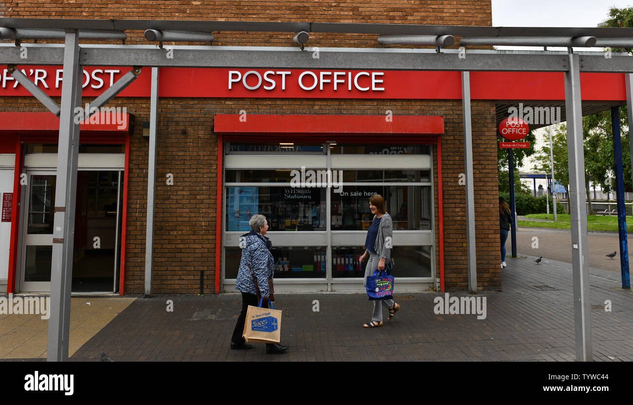 Exterior of a Post Office building in the UK with two people meeting ...