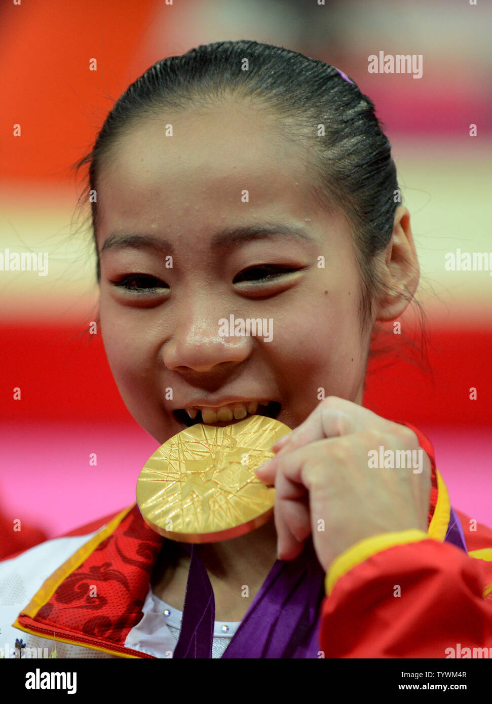 China's Deng Linlin takes a bite of her gold medal she won on the ...