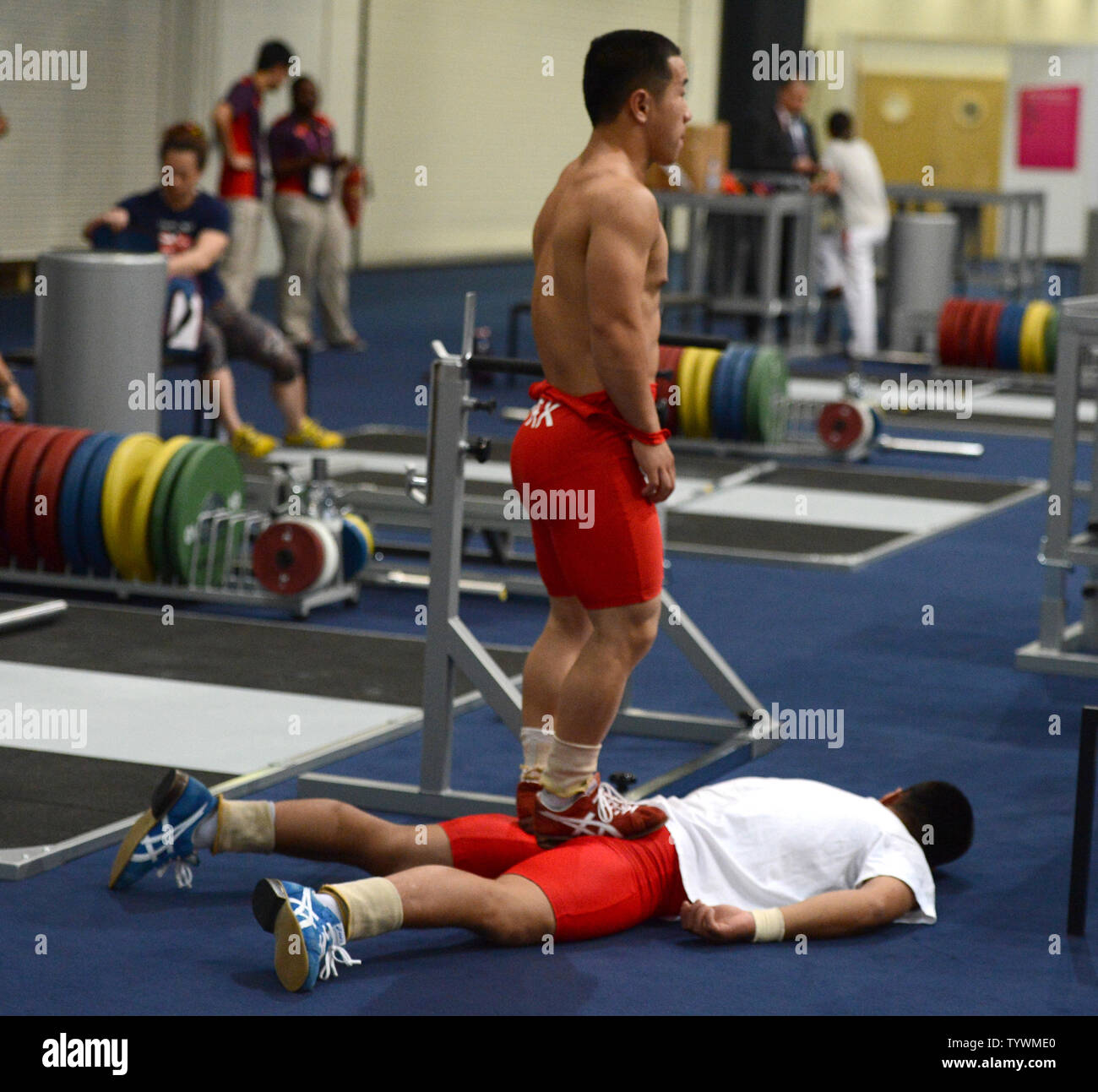 A weightlifter from the Peoples Republic of Korea stands on a teammate ...