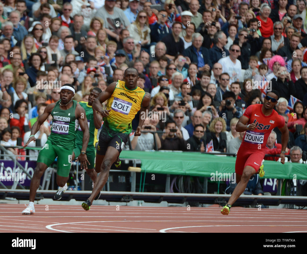 Usain Bolt of Jamaica (C) rounds the turn with Noah Akwu of Nigeria (L ...