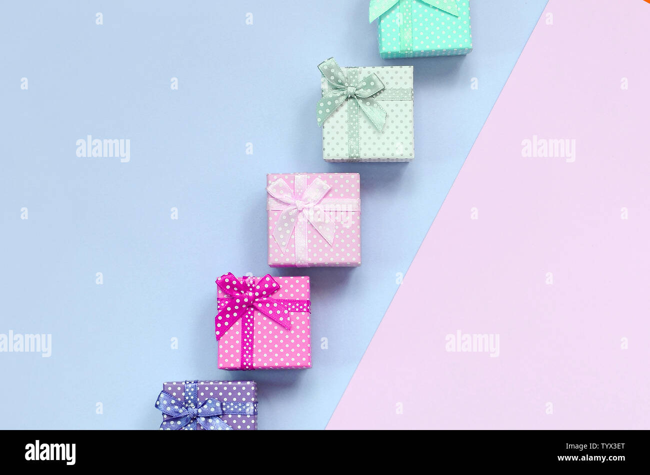 Small gift boxes of different colors with ribbons lies on a violet and ...