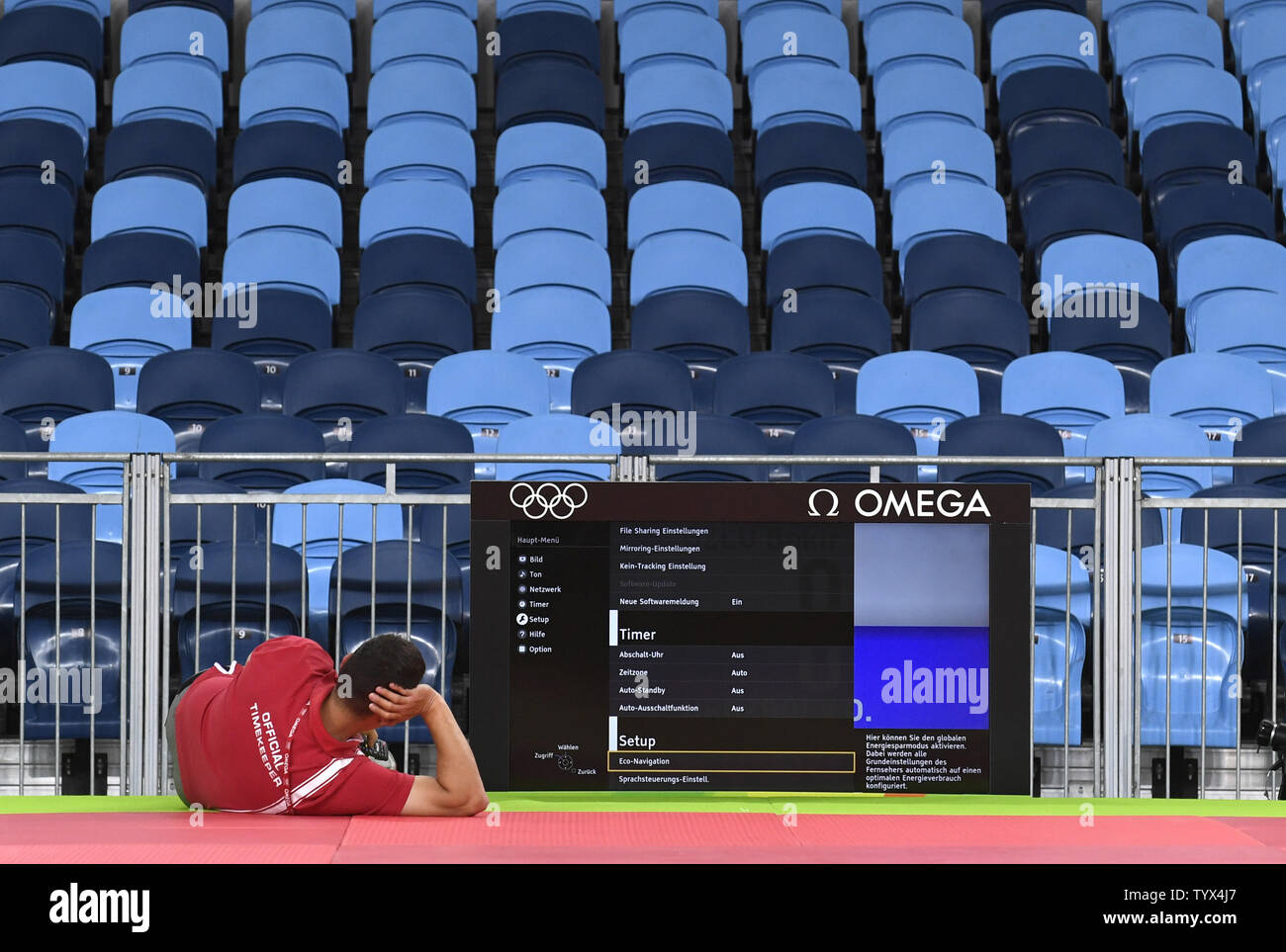 A technician calibrates a scoring monitor before empty seats at a venue ...