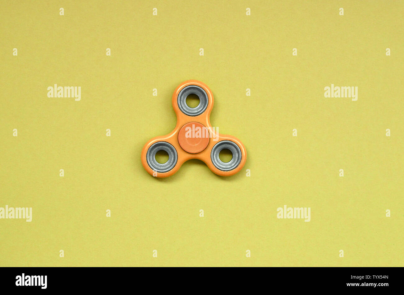 orange fidget spinner lies on texture background of fashion pastel ...