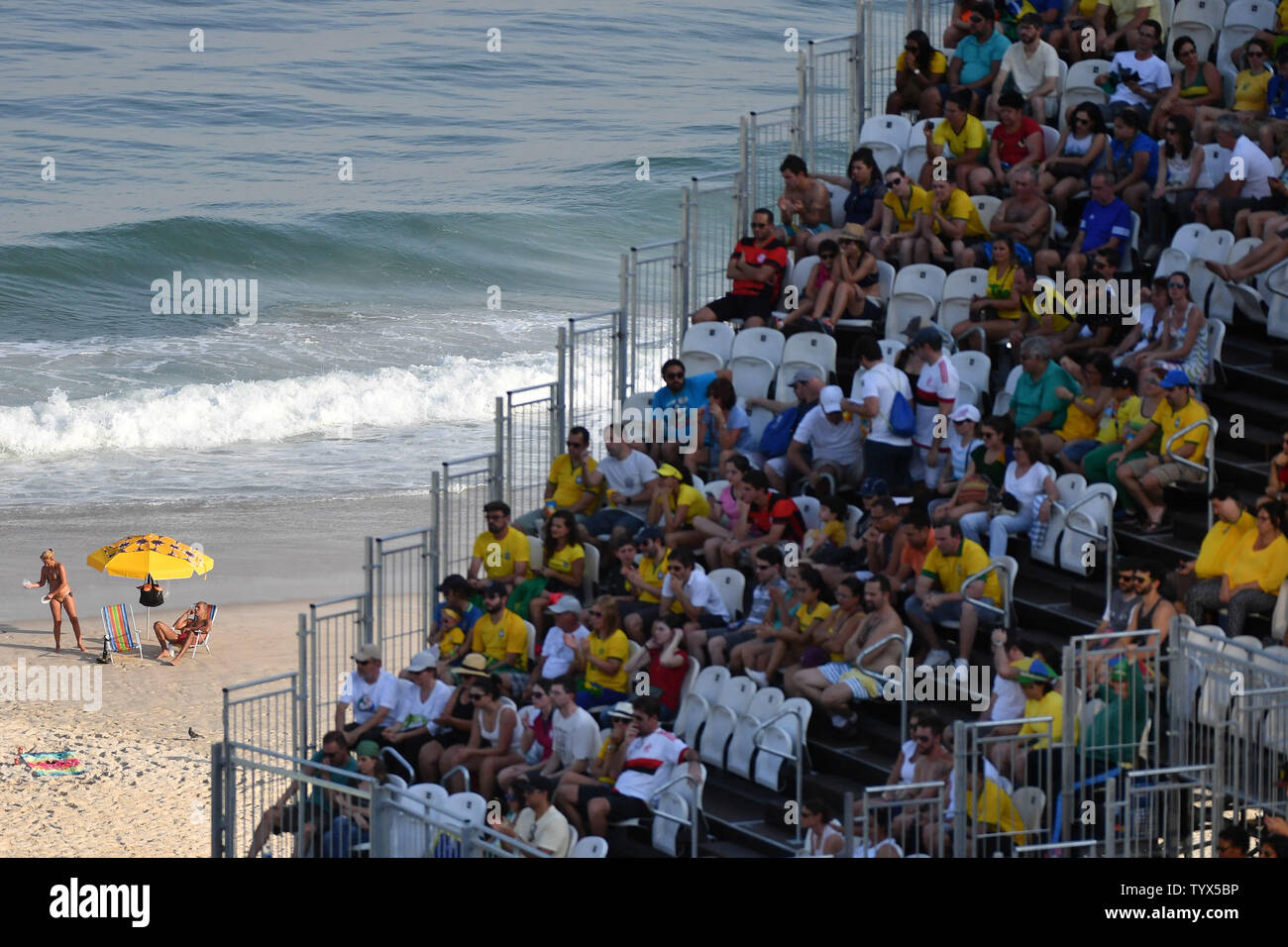Beach goers are seen framed with the bleachers at the volleyball venue ...