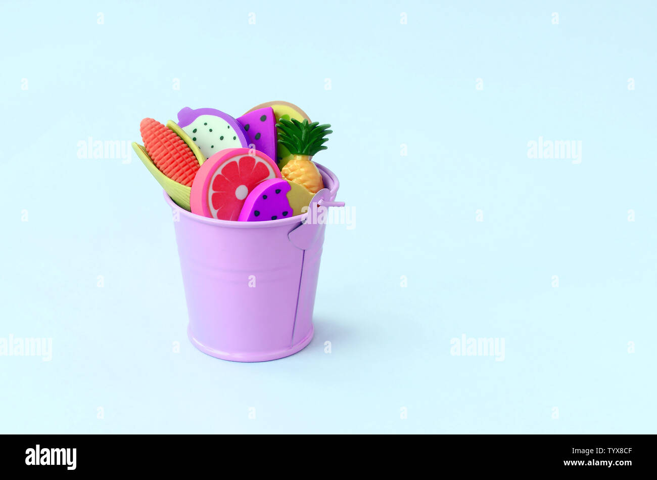 Various fresh fruits in a small violet pail on blue background ...