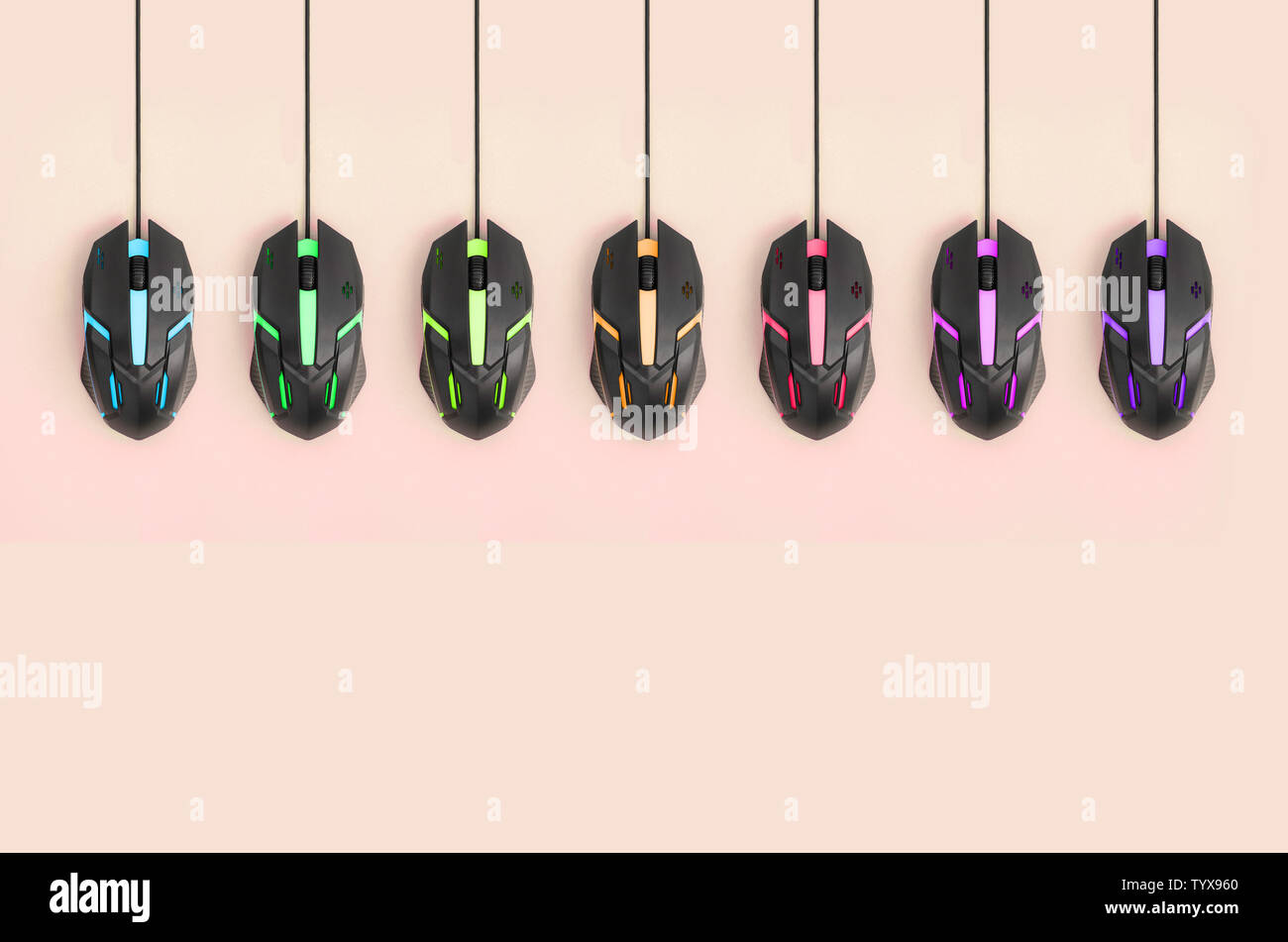 Several computer mice hang on a pastel peach background. The concept of ...