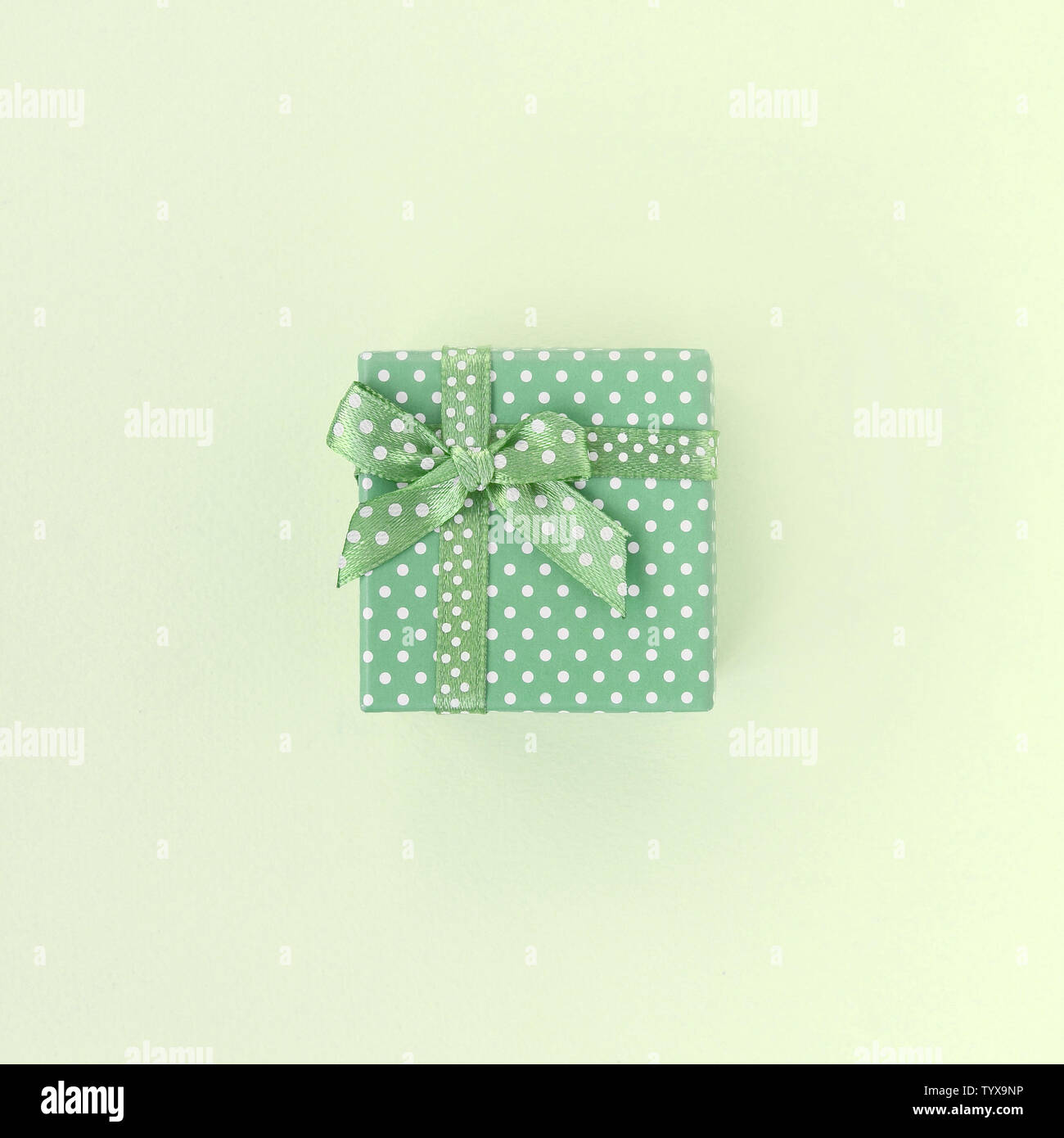 Small green gift box with ribbon lies on a lime background. Minimalism ...