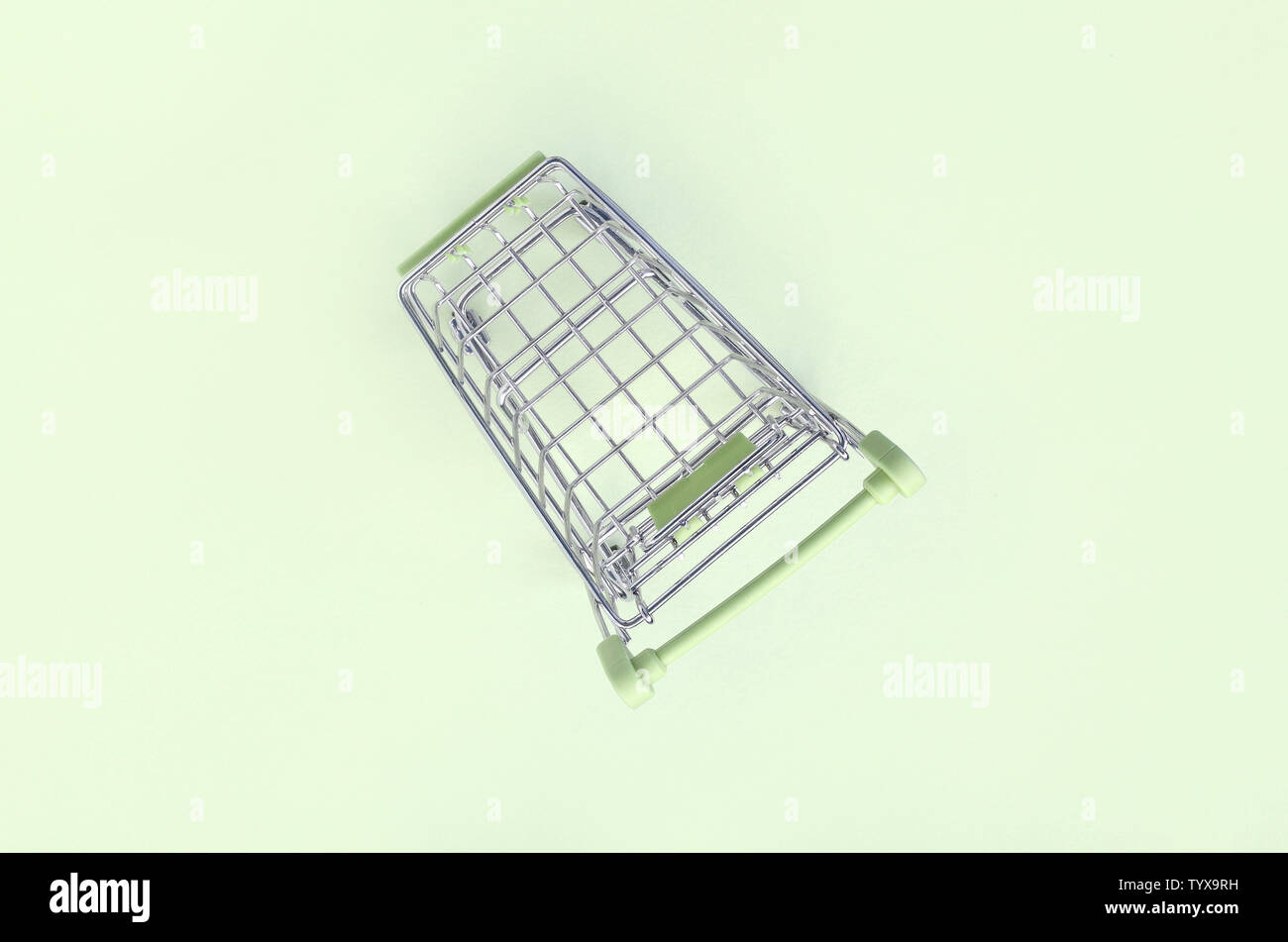 Small shopping cart lies on a lime background. Minimalism flat lay top ...