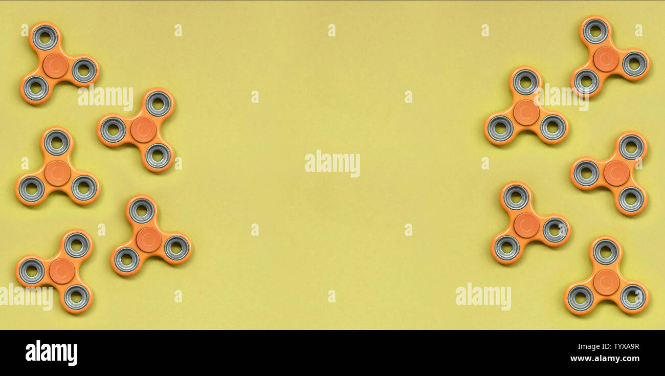 Many orange fidget spinners lies on texture background of fashion ...