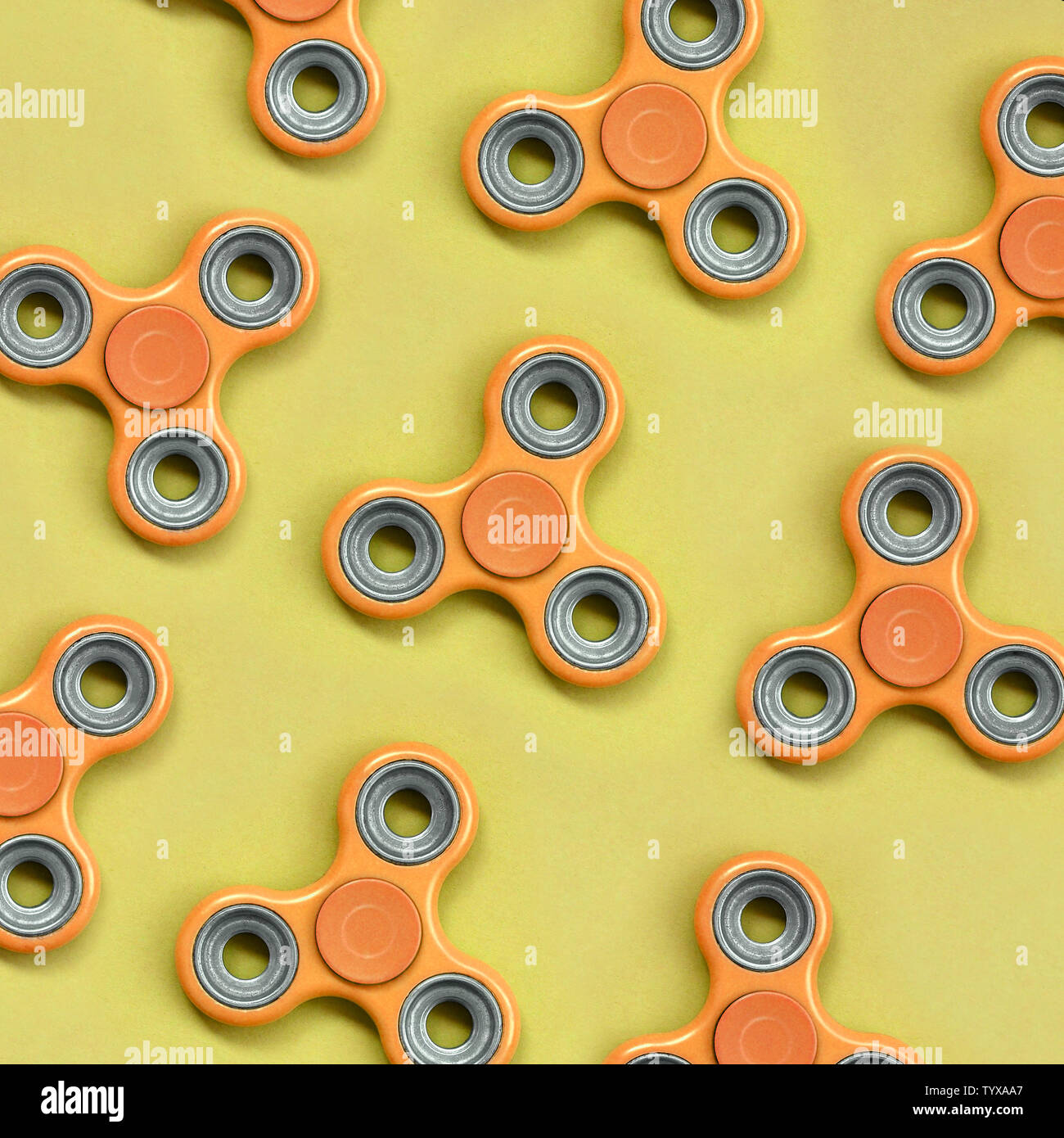 Many orange fidget spinners lies on texture background of fashion ...