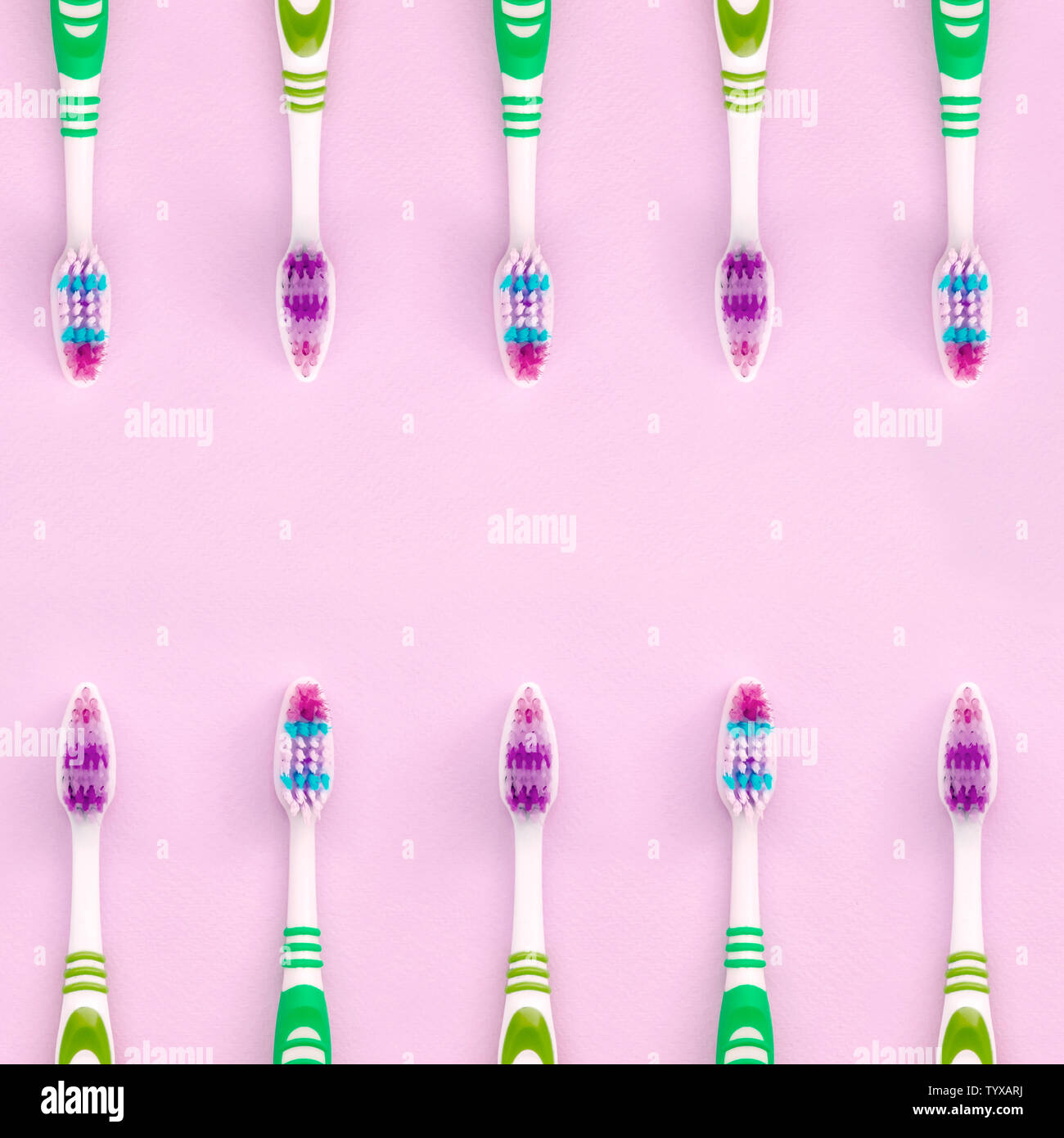 A lot of toothbrushes lie on a pastel pink background. Top view, flat ...
