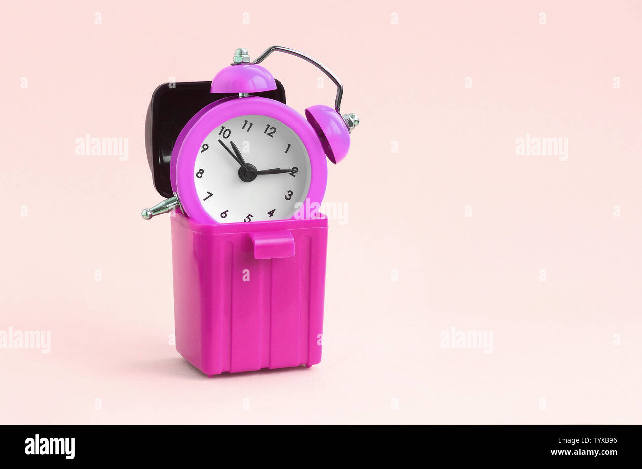 Wasting time concept. Pink alarm clocks in plastic trash bin on peach ...