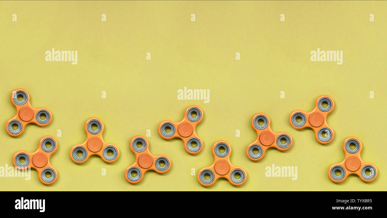 Many orange fidget spinners lies on texture background of fashion ...