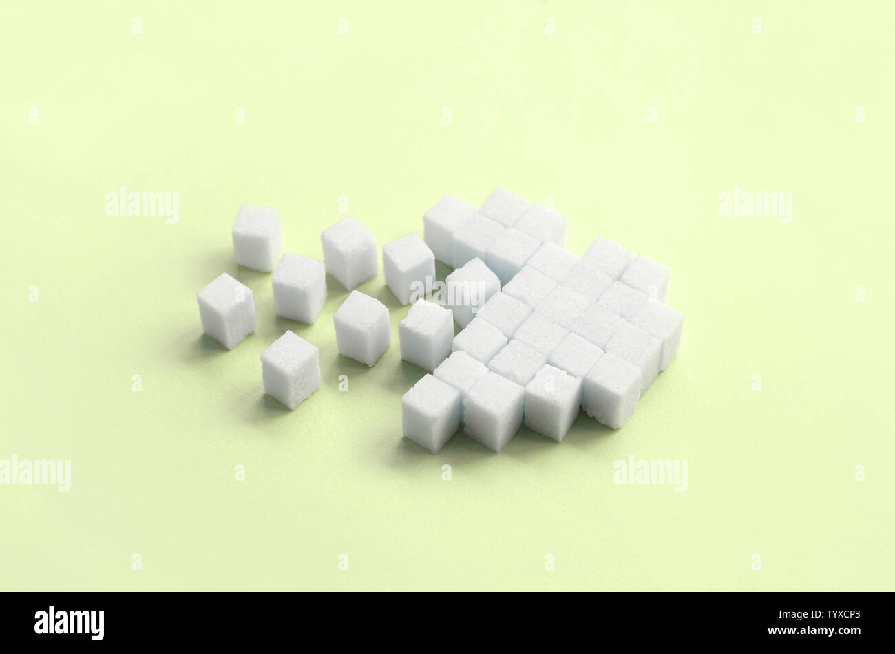 A broken heart made of sugar cubes lies on a trendy pastel lime ...