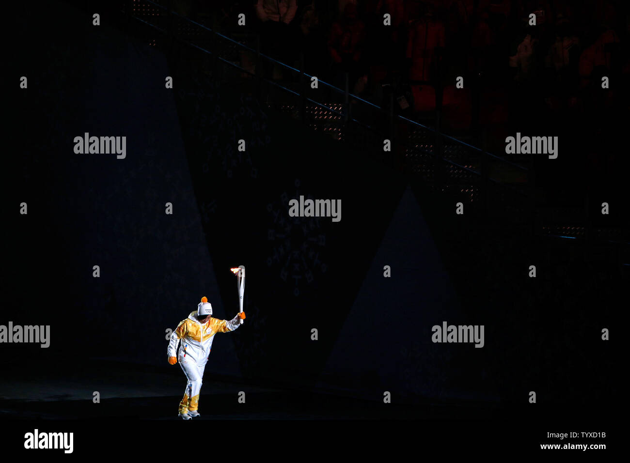 The Olympic torch is carried into the stadium during the opening ...