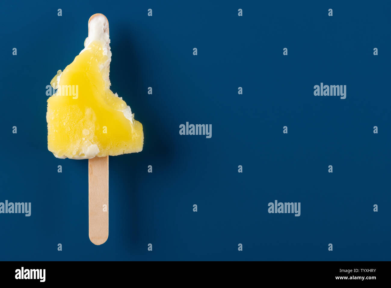 half eaten yellow popsicle on a blue background Stock Photo - Alamy