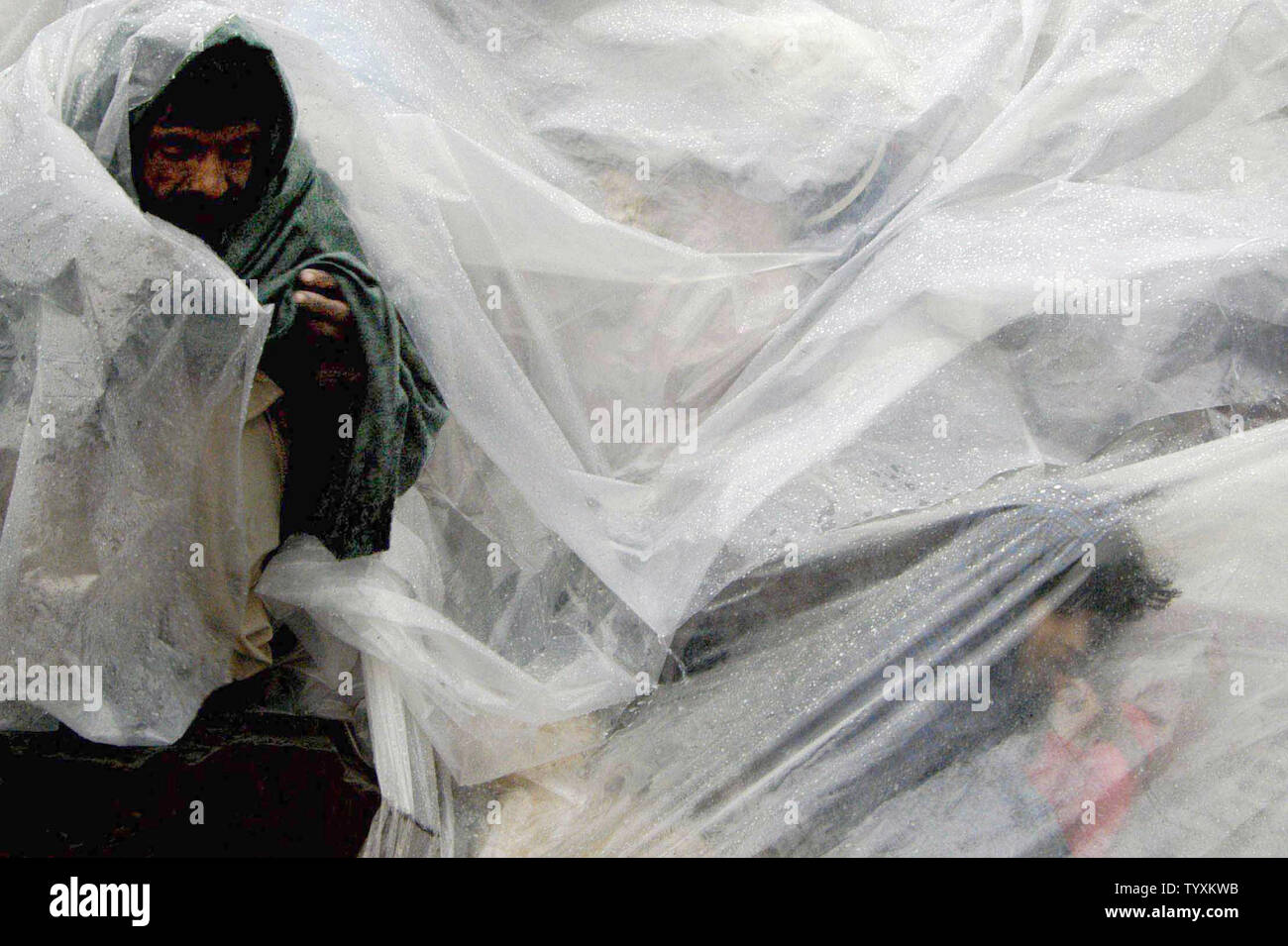 A Pakistani man and his boy,take shelter from the rain in Balakot ...